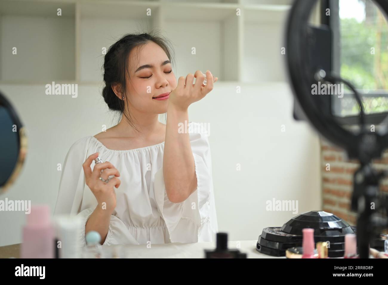 Pretty woman beauty blogger spraying perfume on her wrist while ...