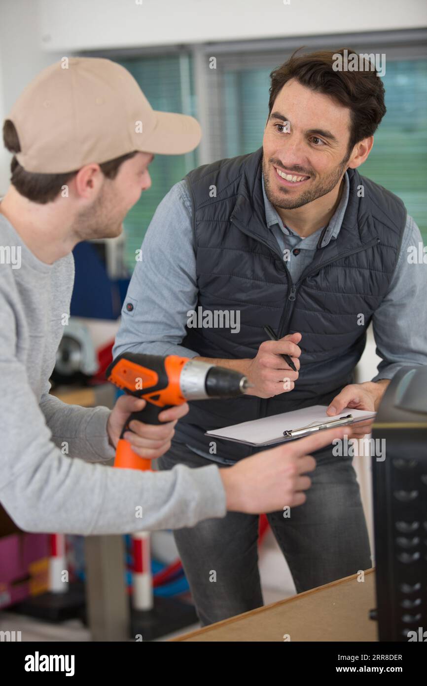 two men in workwear in a carpenters workshop with parcel Stock Photo ...