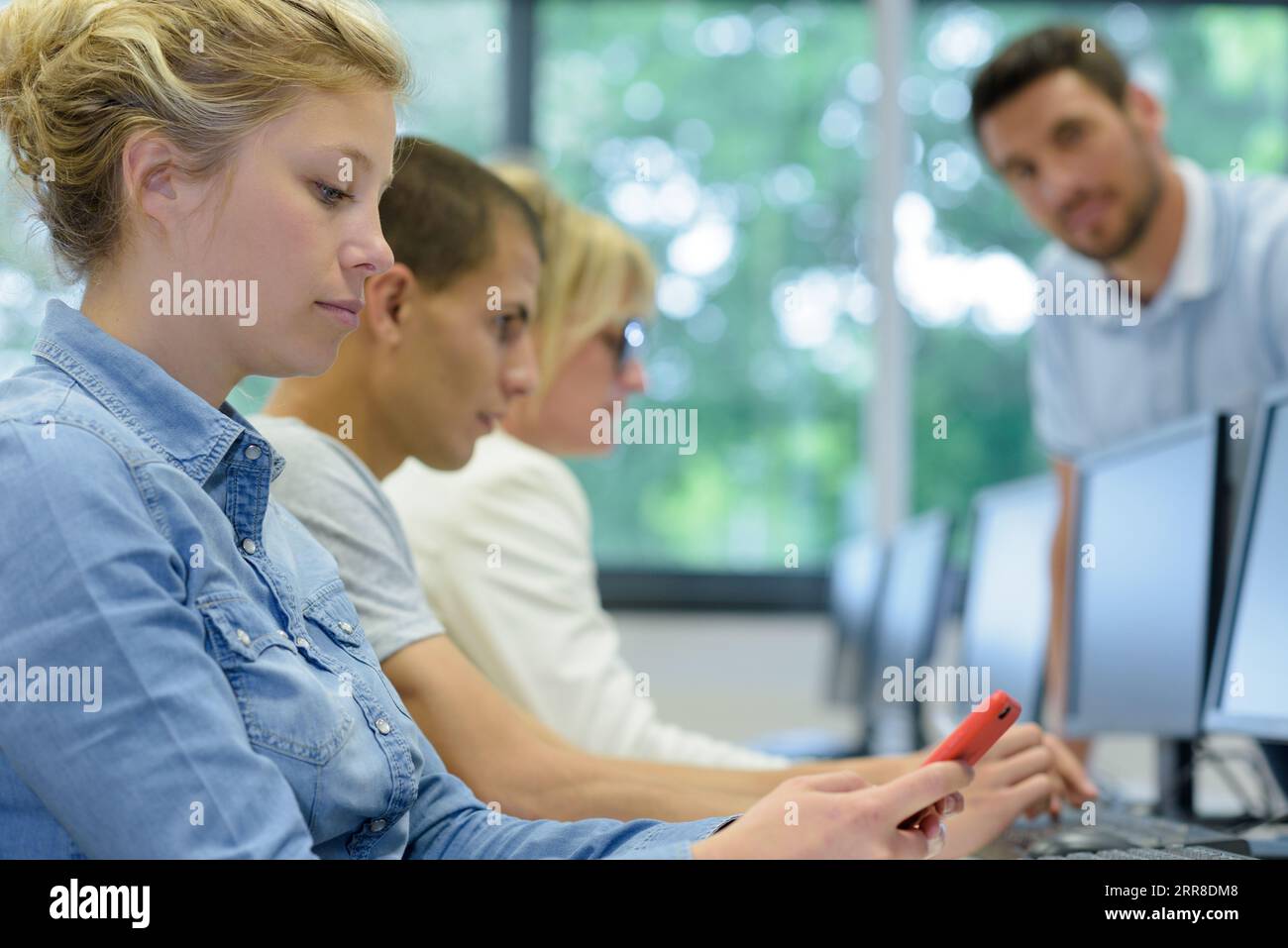 adolescent girl using smartphone during computer class Stock Photo - Alamy