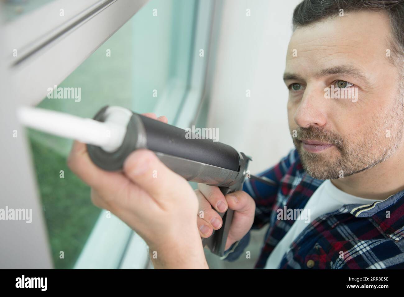 man with silicone sealant fixing a window Stock Photo - Alamy