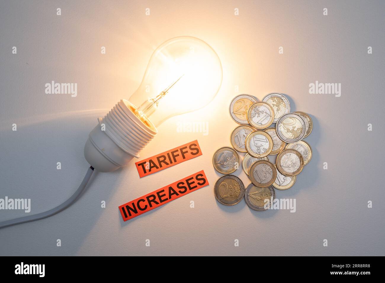 Lit light bulb, next to coins and text Tariffs increases. Increased ...