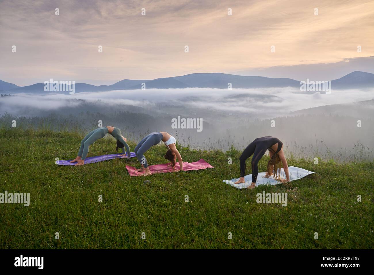 Group of three sporty women in activewear doing stretching exercises ...
