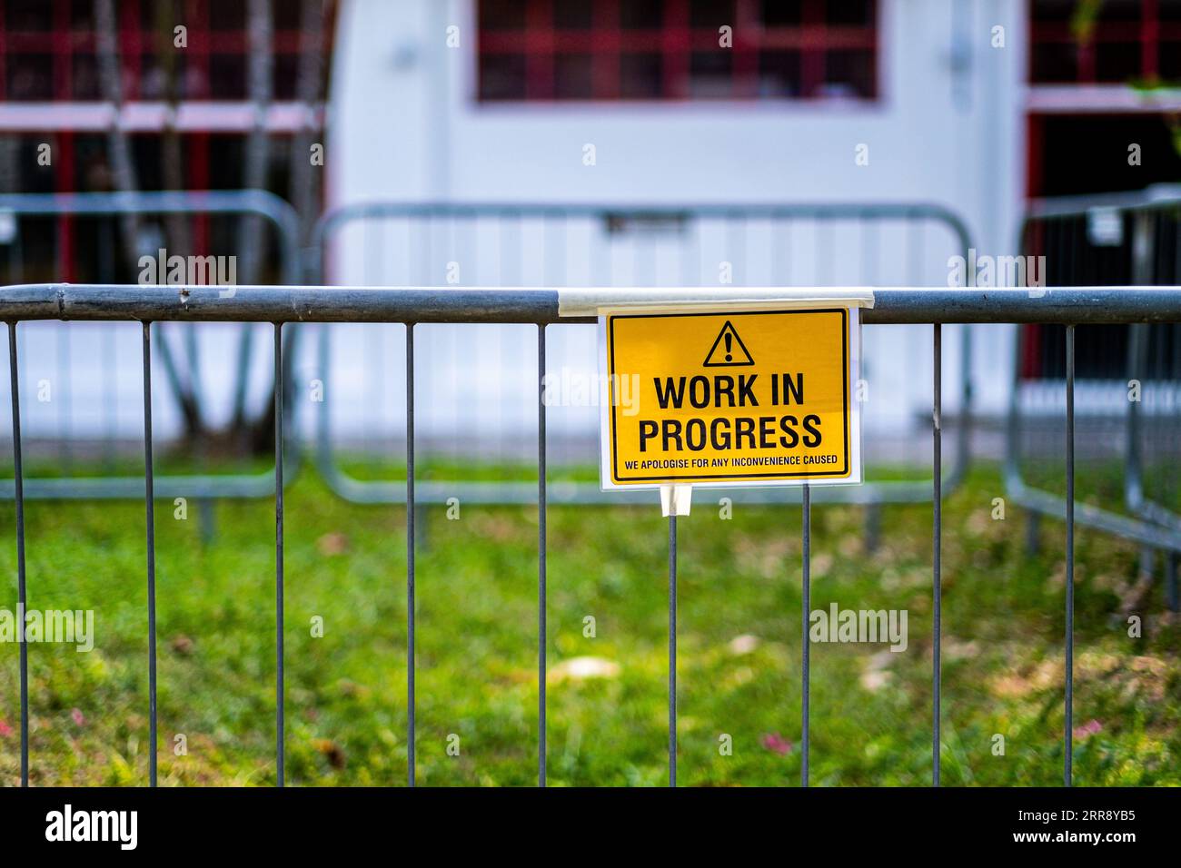 Work in progress sign on iron fence Stock Photo - Alamy
