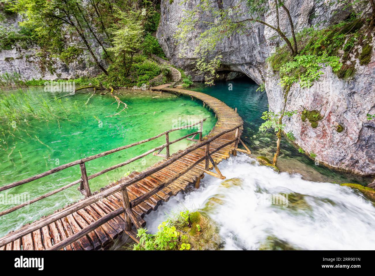 Scenic view of wooden deck over waterfall surrounded by mountains at ...
