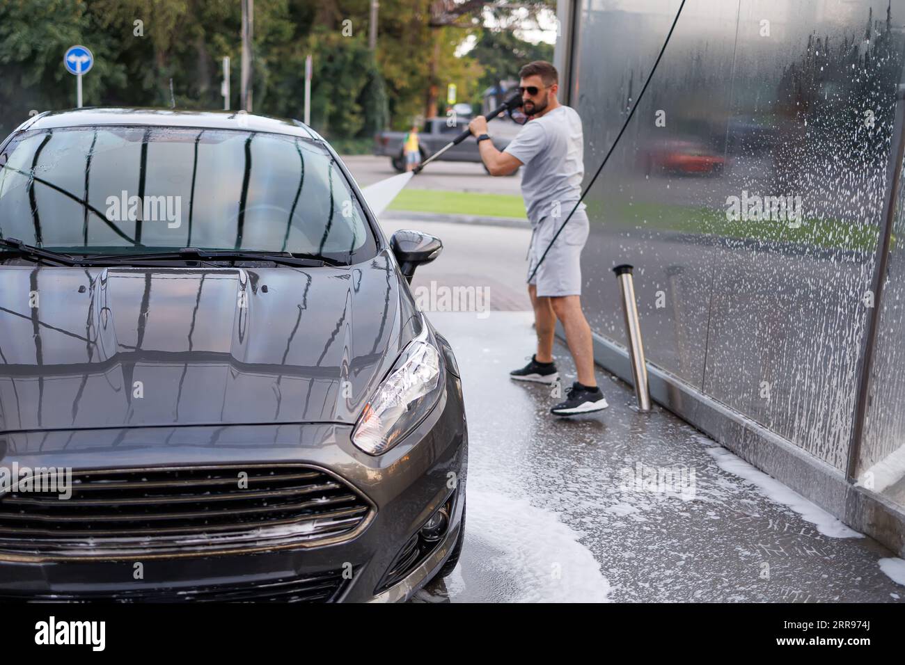 Washing the front of the car being washed by the man in the background ...