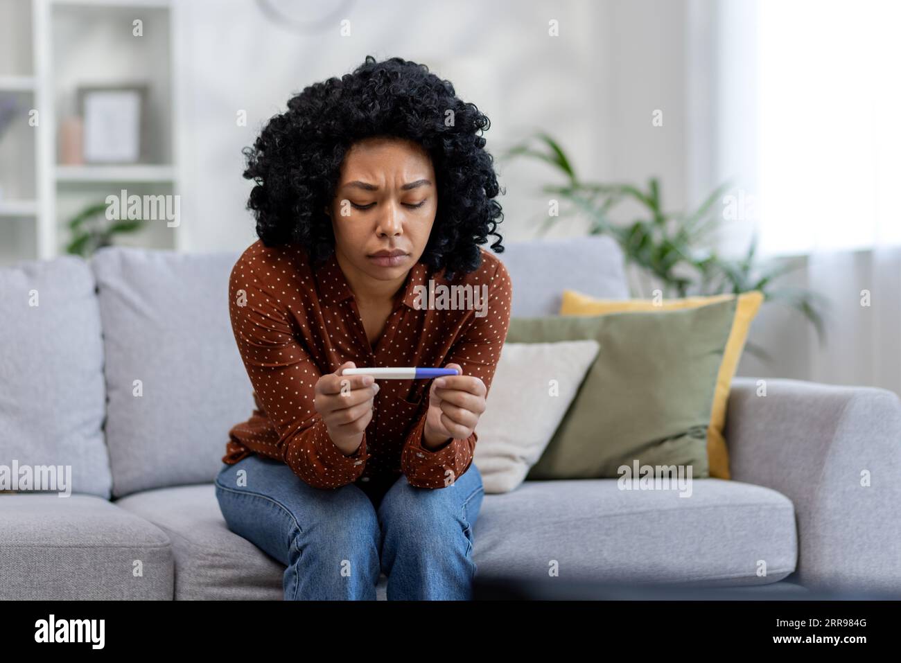 Upset And Pensive African American Young Woman Sitting On Sofa At Home