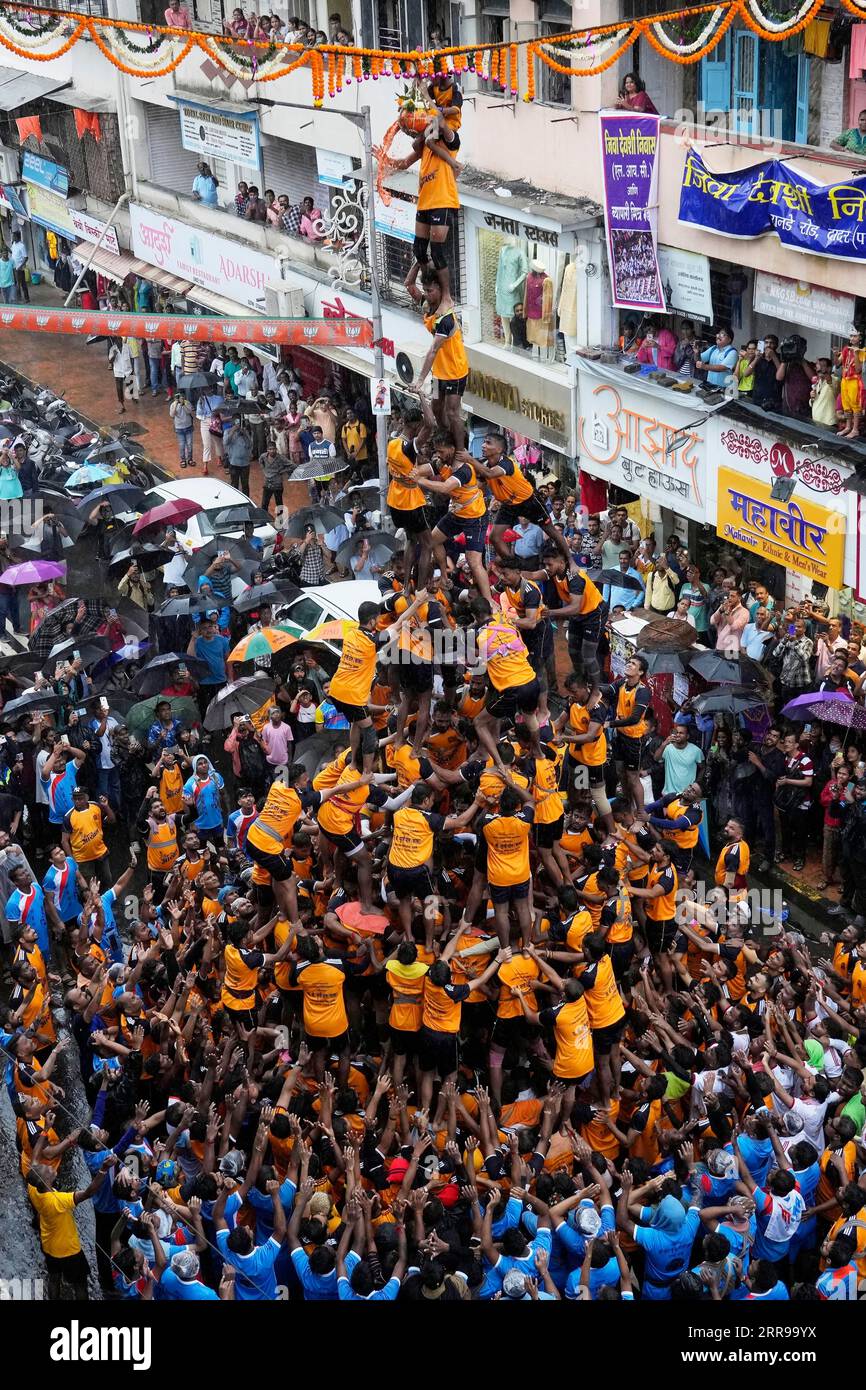 Revelers form human pyramids to reach an overhanging earthen pot while ...