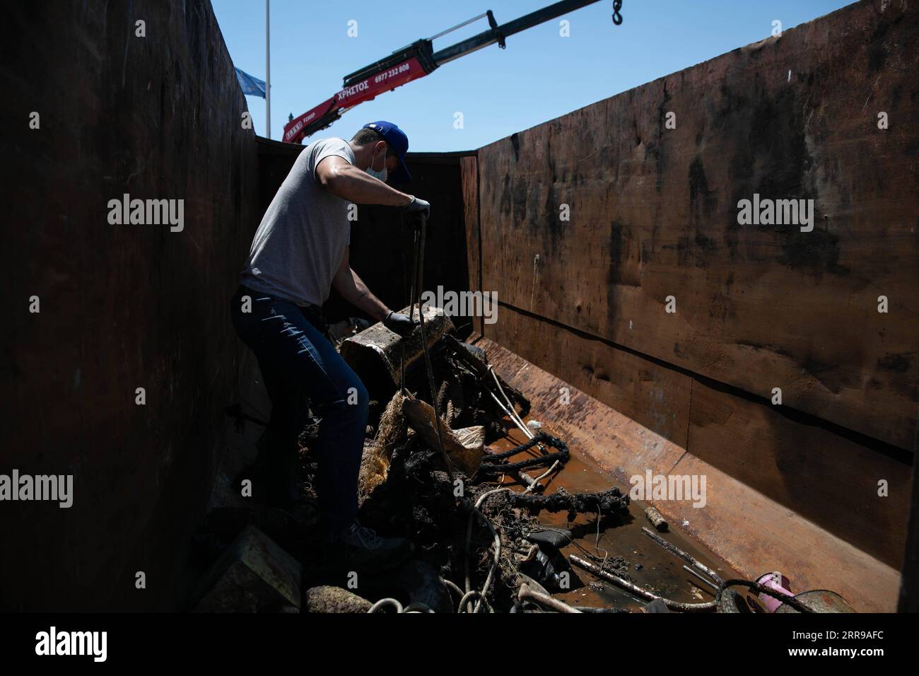 210605 -- RAFINA GREECE, June 5, 2021 -- A volunteer puts waste into a ...