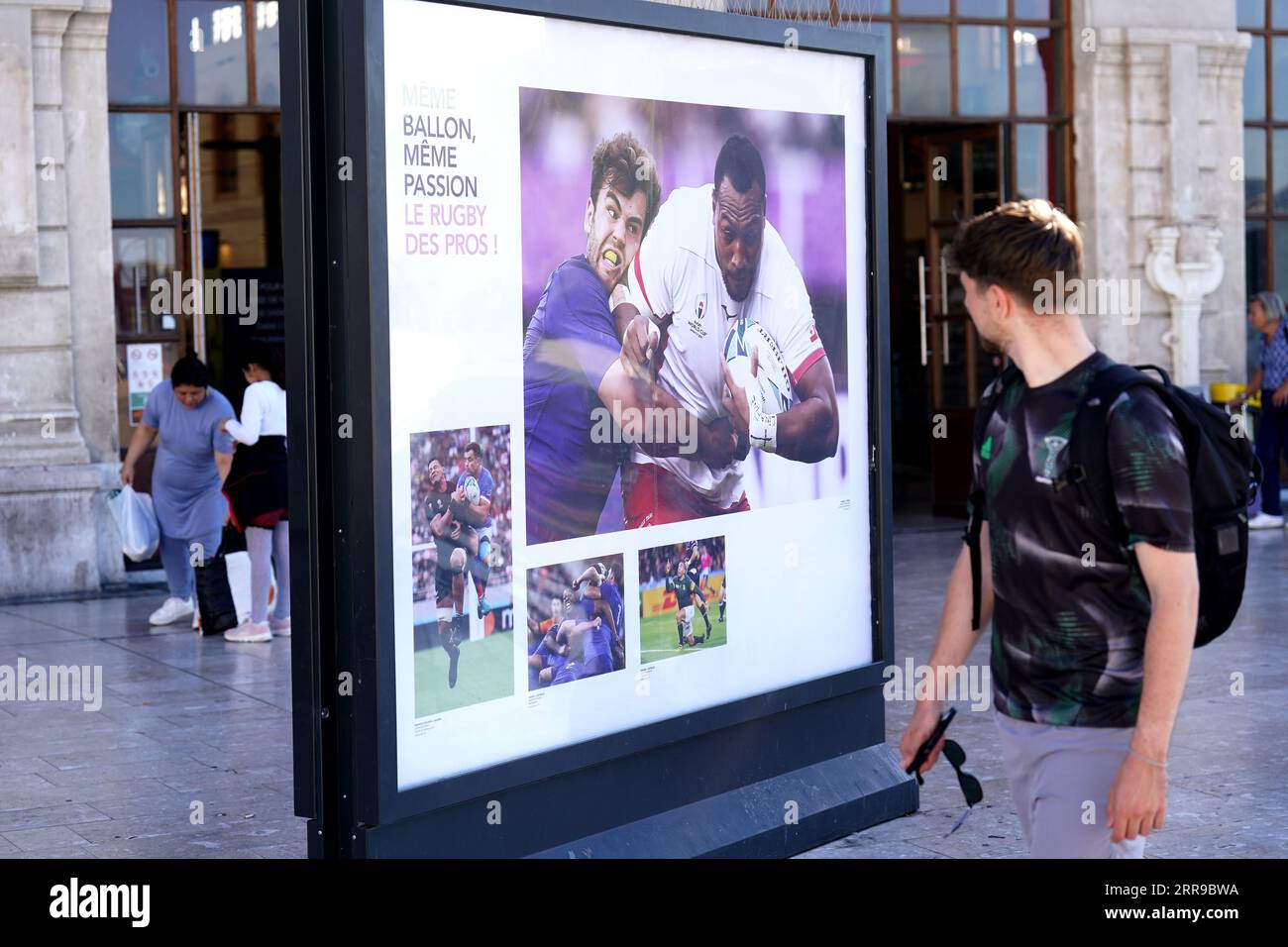 A person looks at a billboard featuring images of rugby players in ...