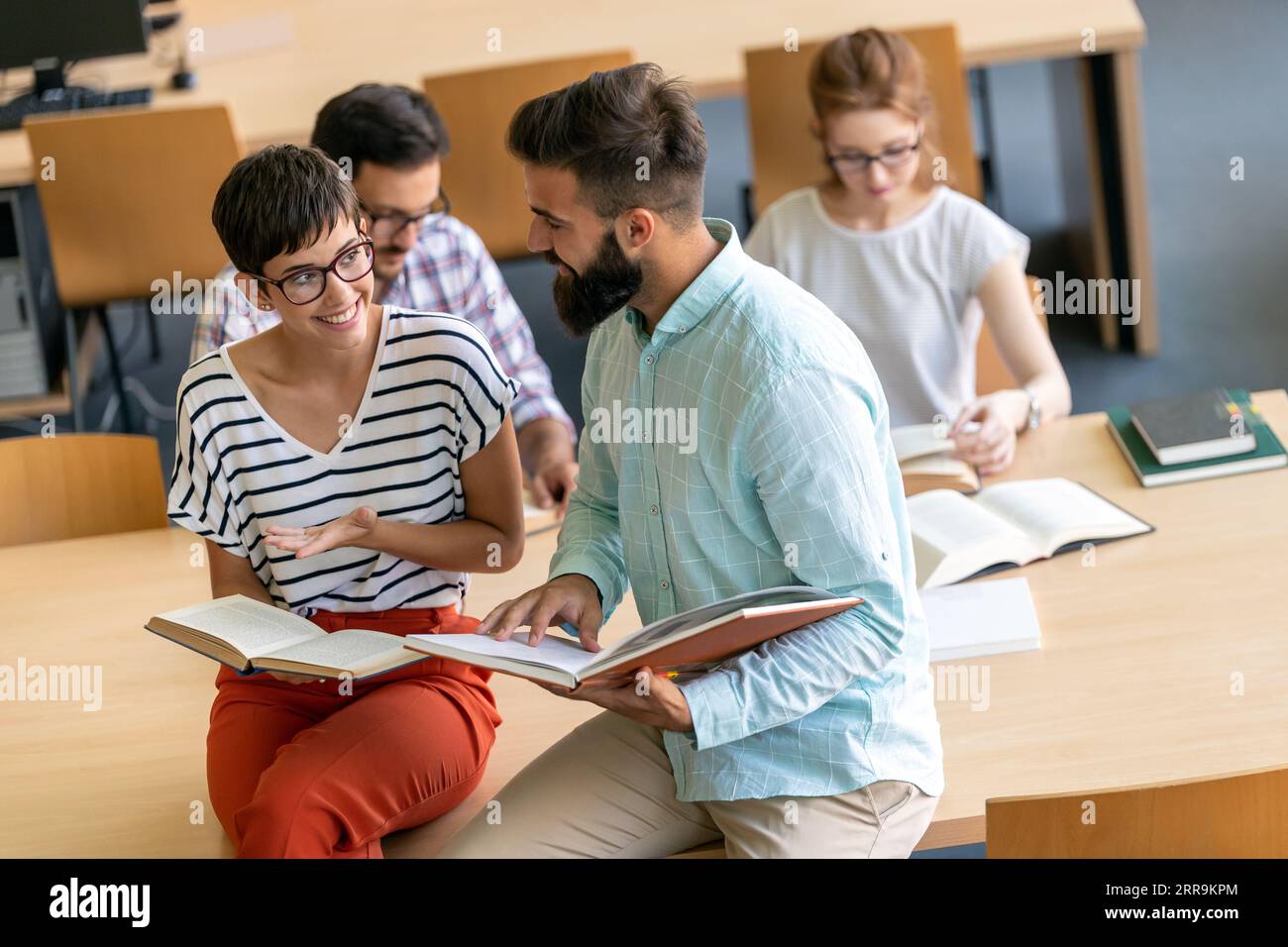 Happy university students studying with books in library. Group of ...