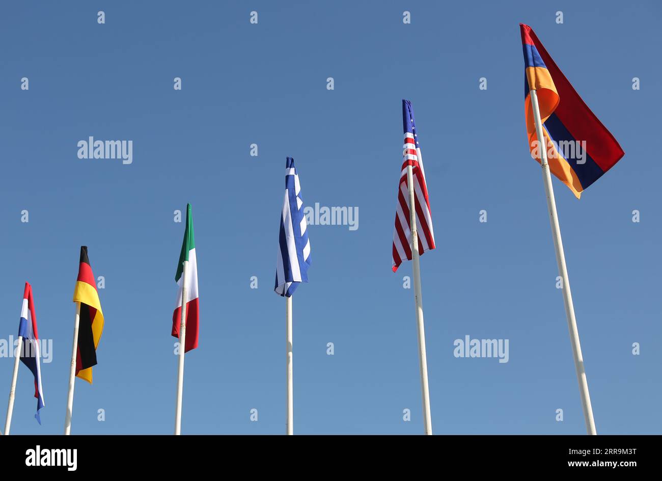 A low angle of various country flags on poles against blue sky Stock ...