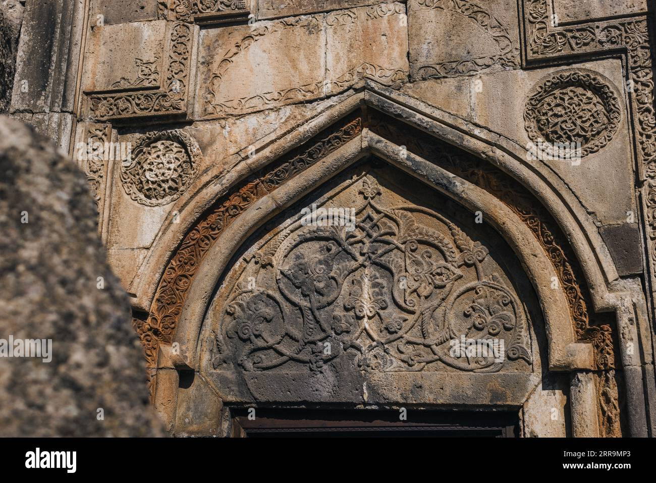 An aged door of a stone Christian church with intricate stone patterns ...