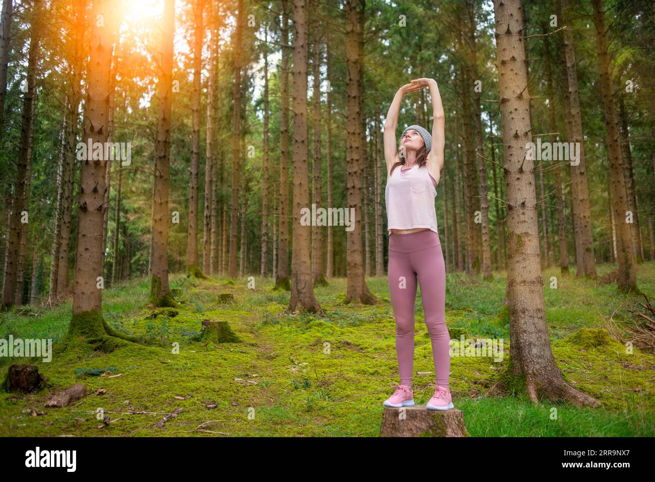fit, sporty woman doing stretching exercises outside in the forest ...