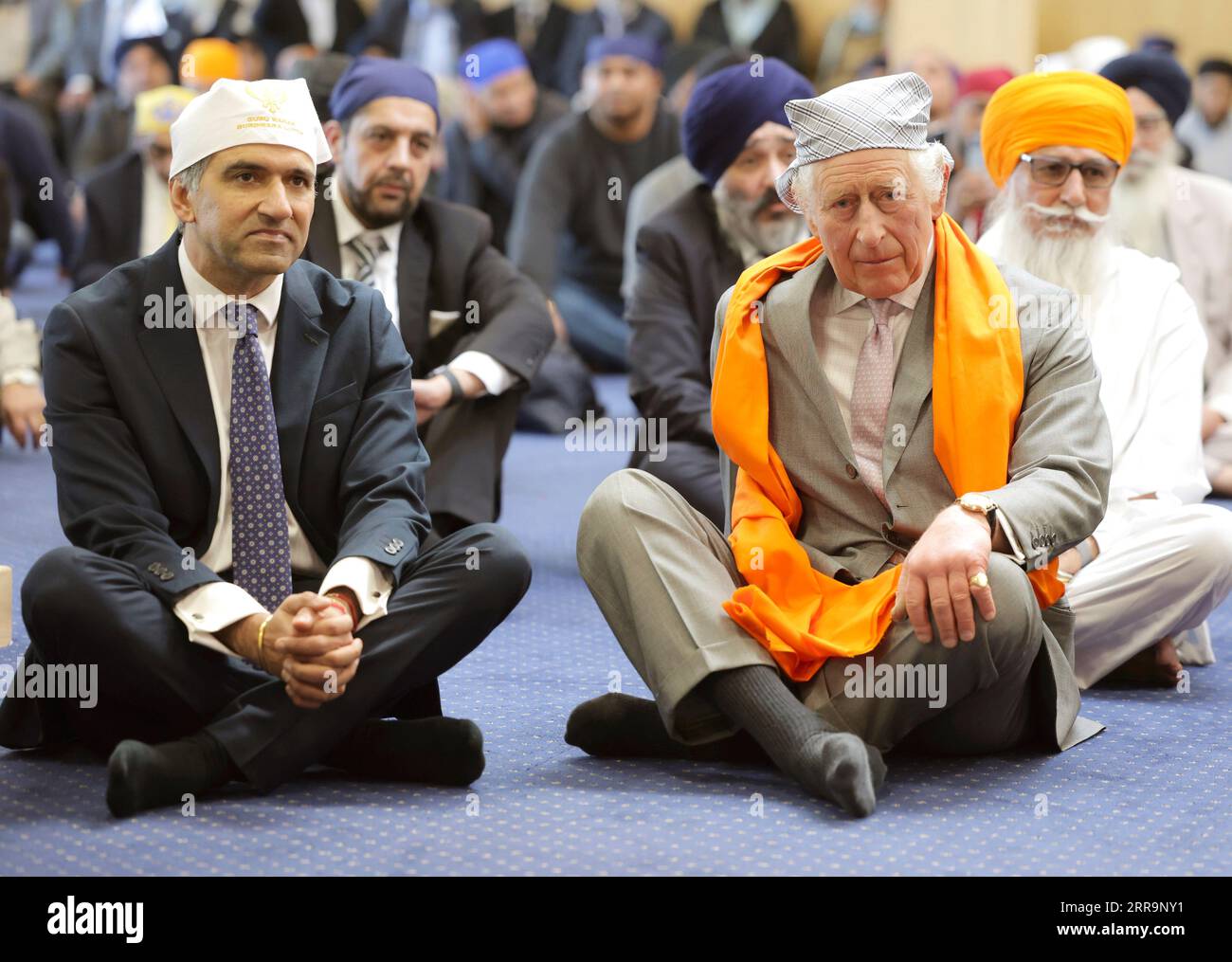 FILE - Britain's King Charles III, right, sits on the floor next to ...