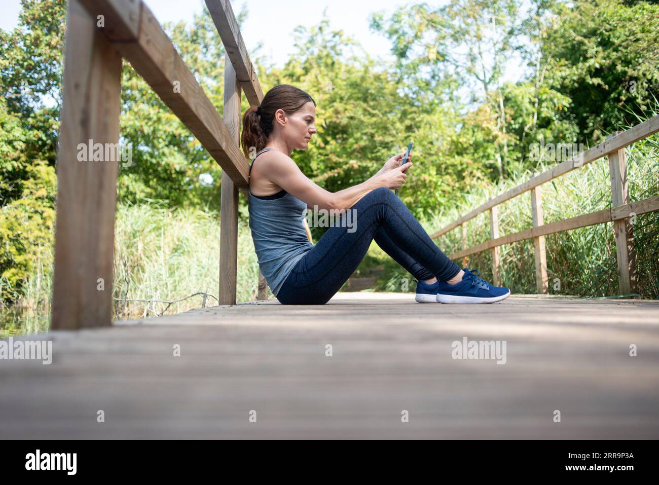 Fit, sporty woman checking her mobile phone while resting after ...