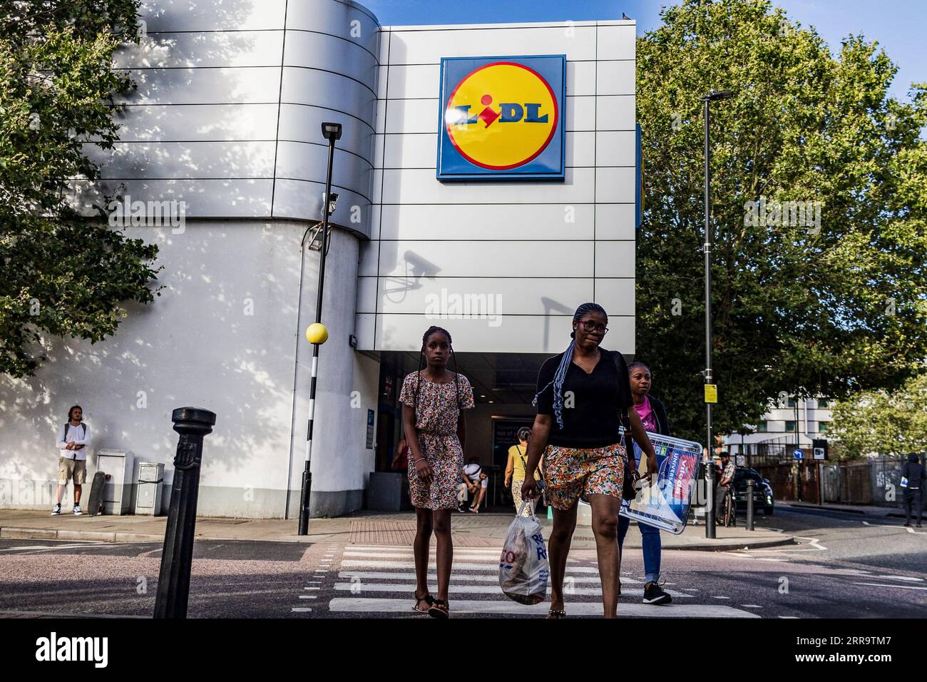 People walk past Lidl, a Germany-headquartered discount retailer chain ...