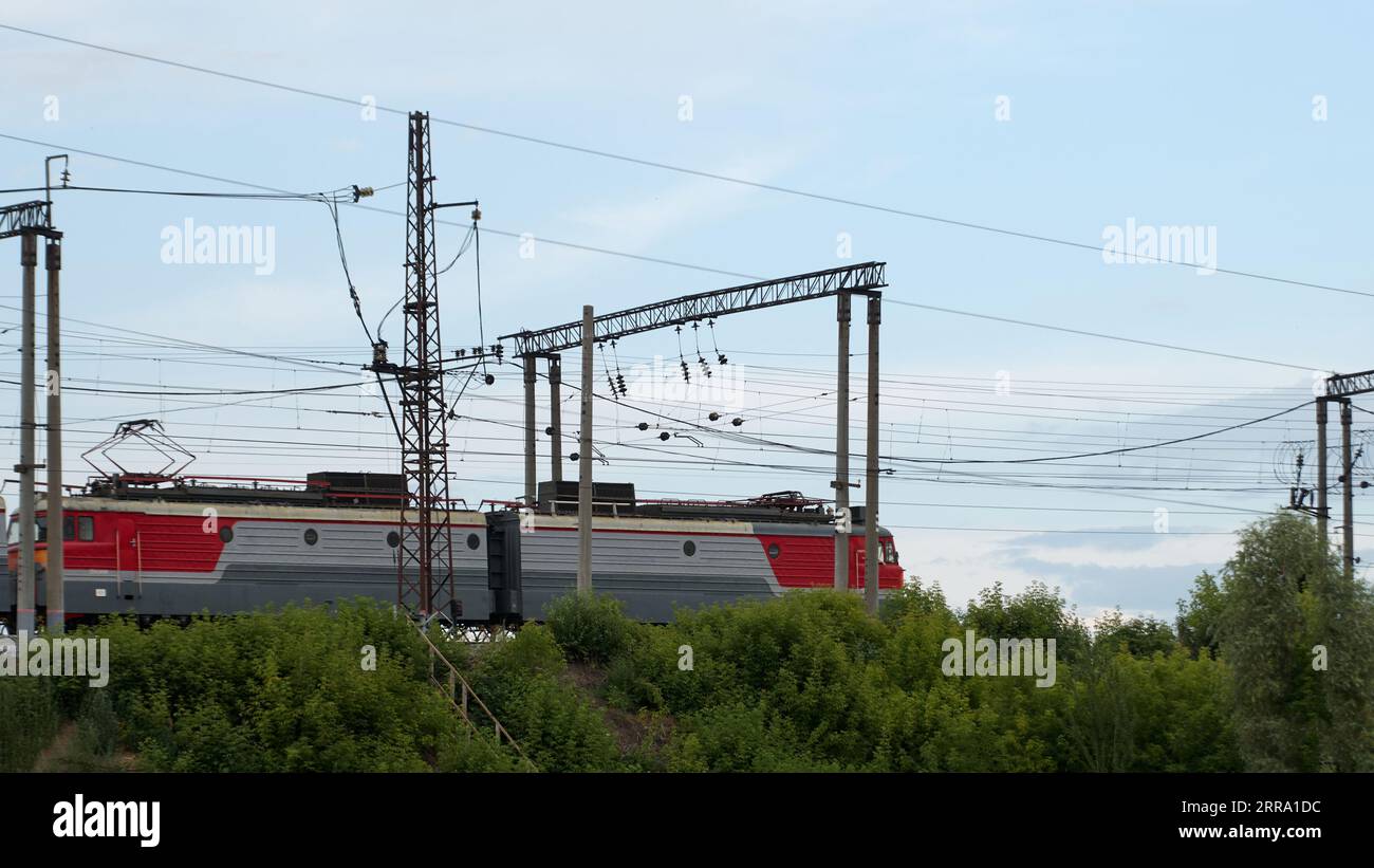 Side view of a twinned red and gray electric locomotive running on a ...