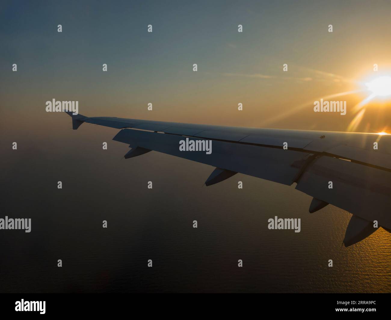 The sun setting behind an aircraft wing on approach to Luga ...