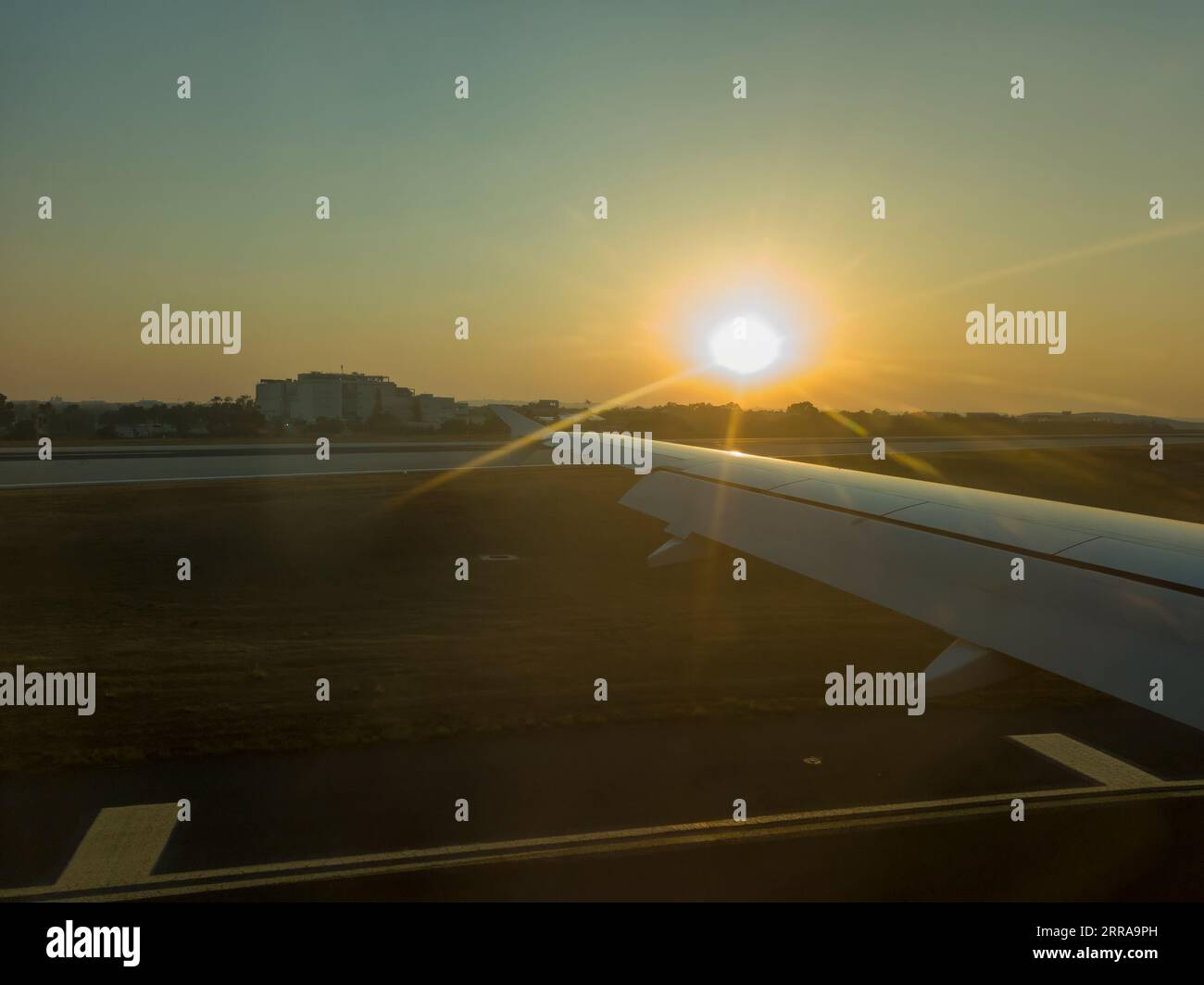 The sun setting behind an aircraft wing on approach to Luga ...