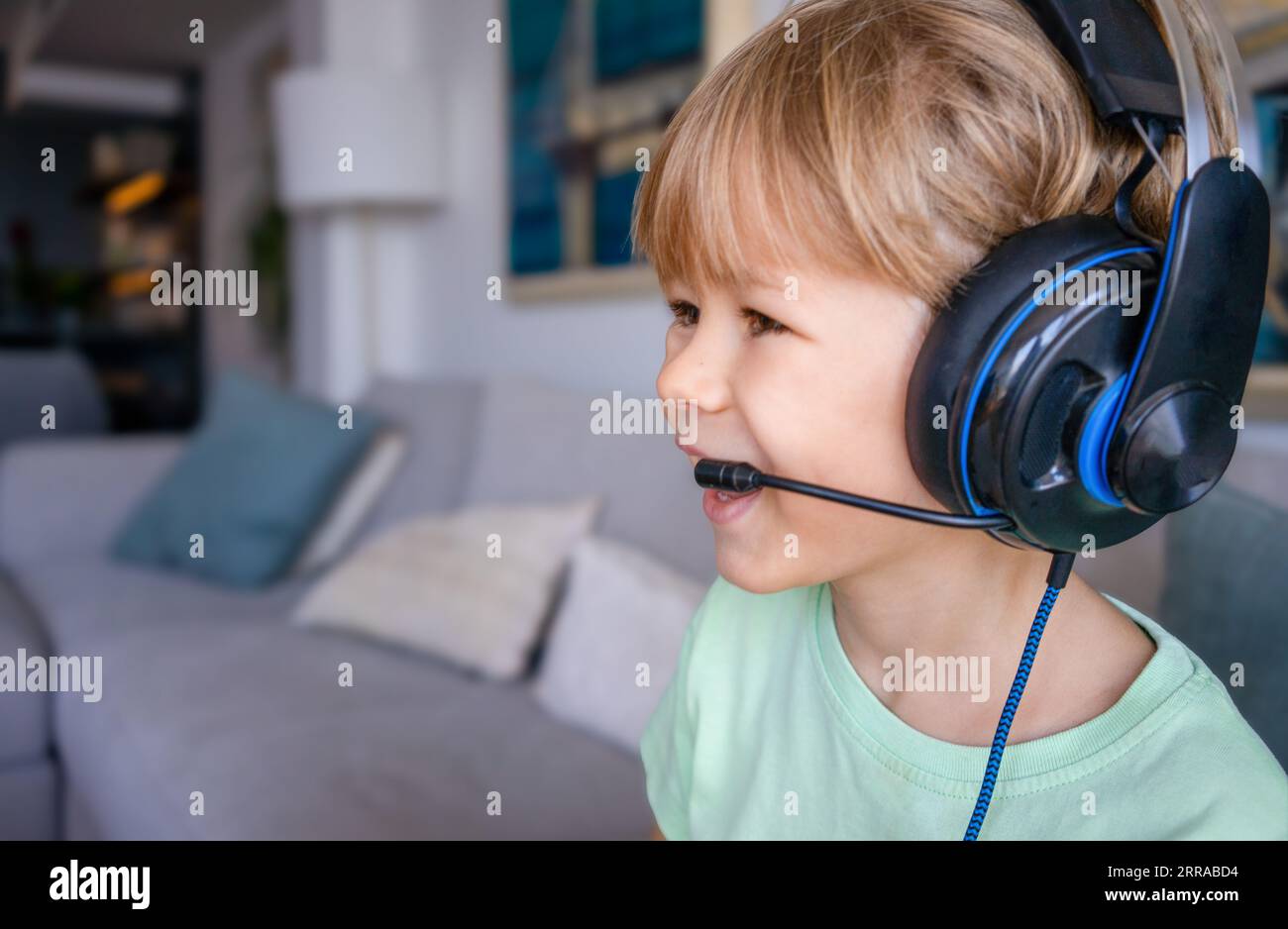 Little child boy with headphones playing video game in living room ...
