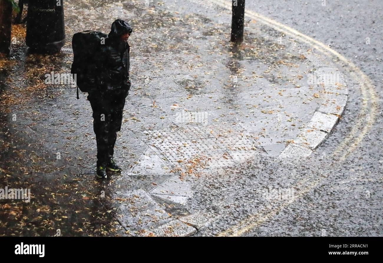 210725 -- LONDON, July 25, 2021 -- A man stands on the roadside during ...