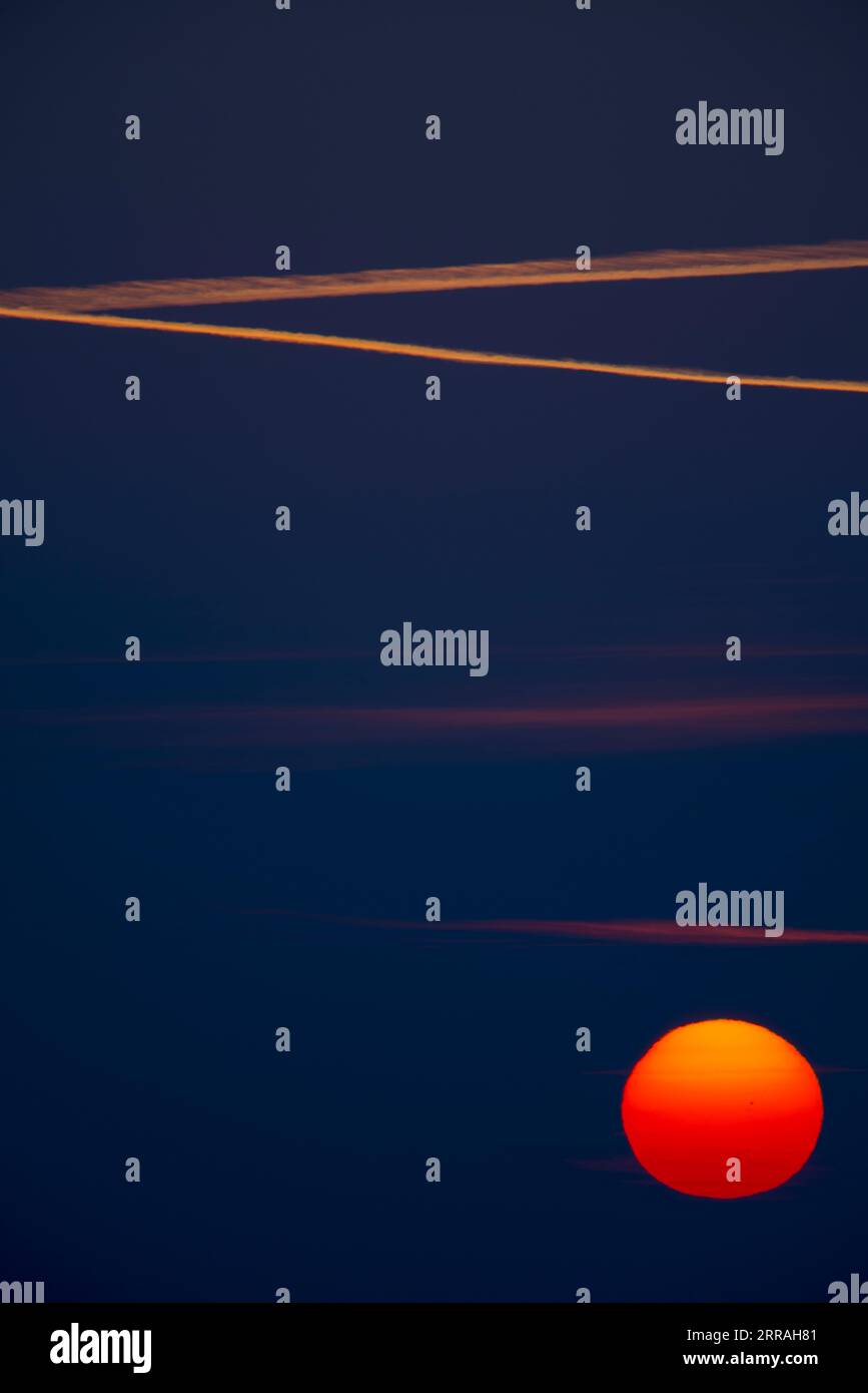 A beautiful sunrise with a deep blue sky, airplane contrails and a ...