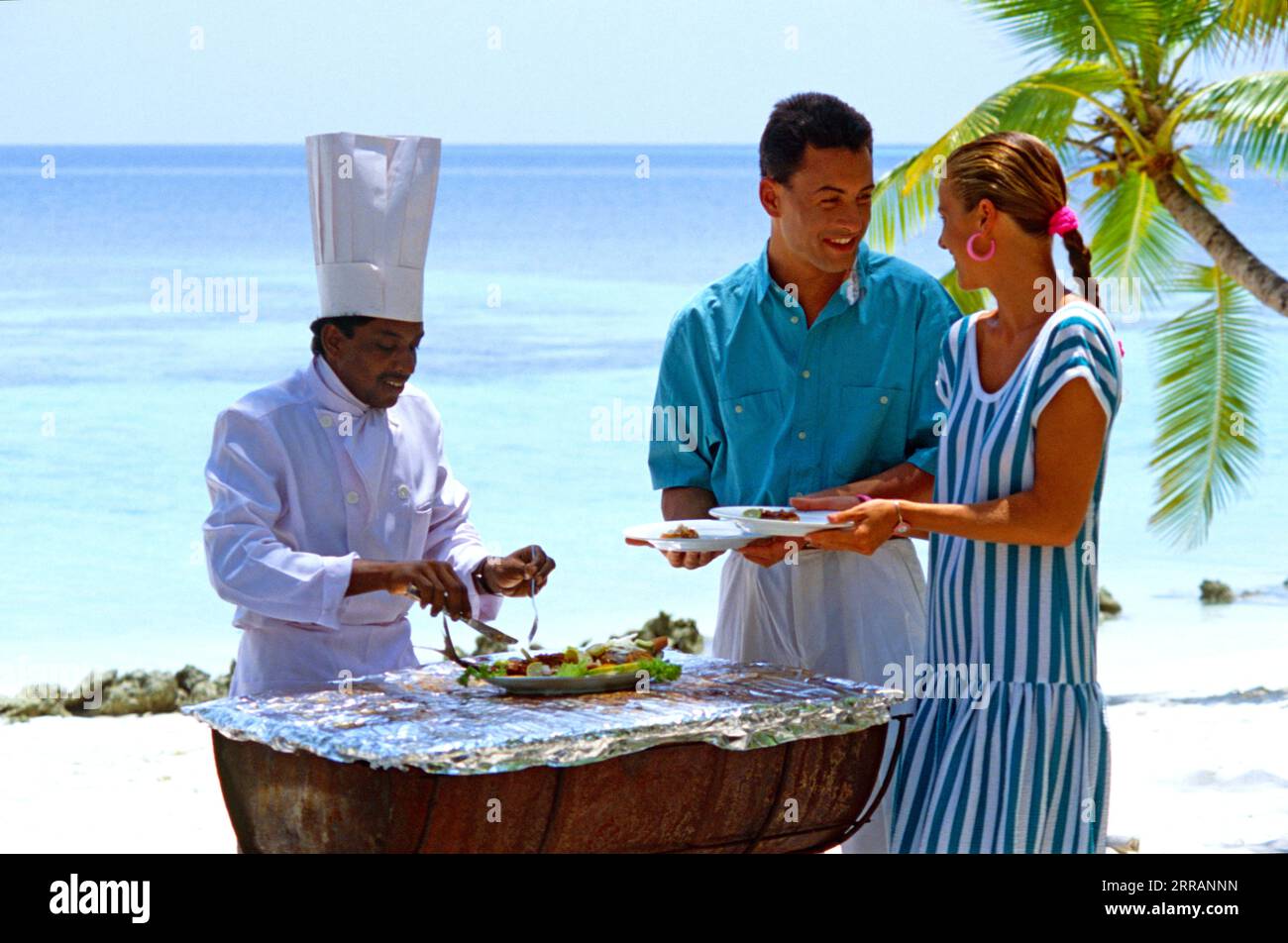 Maldives. Hotel chef serving lunch to young couple on the beach Stock ...
