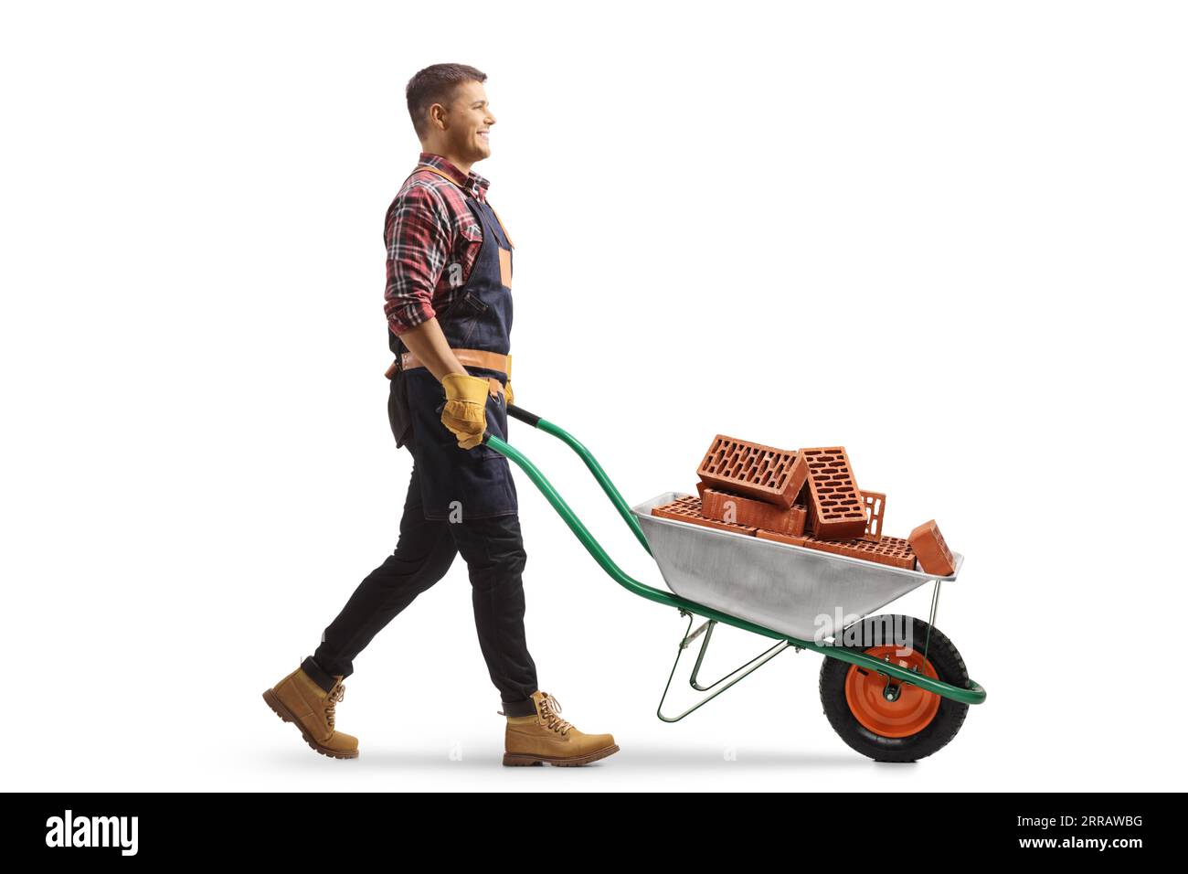Full length profile shot of a young man pushing a wheelbarrow with ...