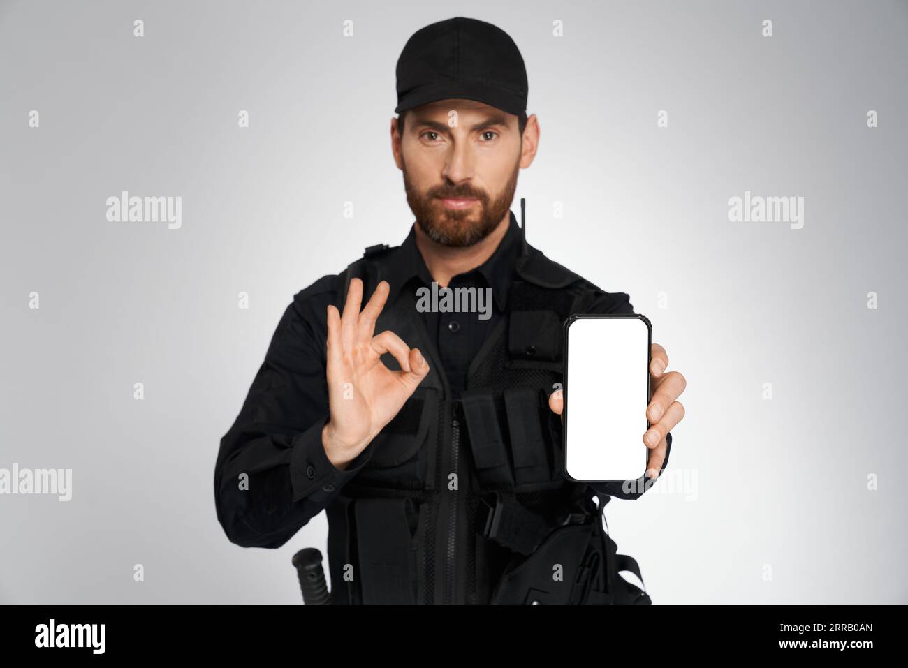 Serious male police officer showing empty mobile phone's screen, with ...
