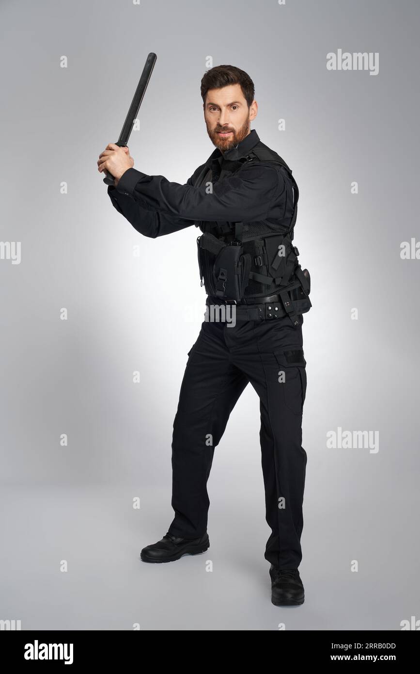 Focused caucasian police officer brandishing with police baton. Front ...