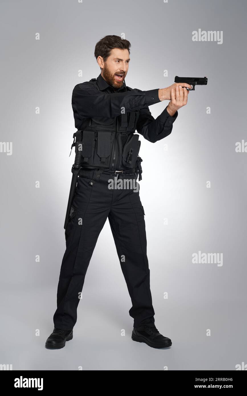 Tensed bearded police officer keeping at gunpoint, while shouting ...