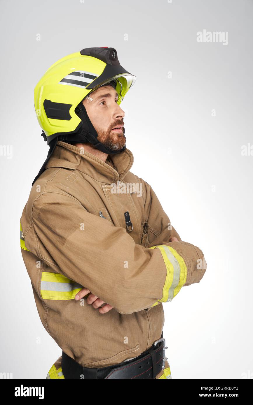 Strong, serious guy in fireman's uniform looking up and away in studio ...