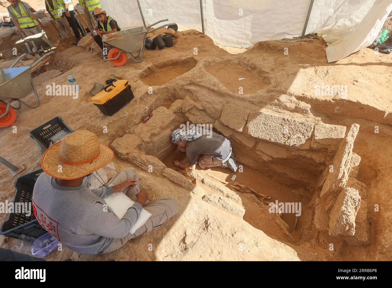 French and Palestinian archaeologists work among graves full of bones ...