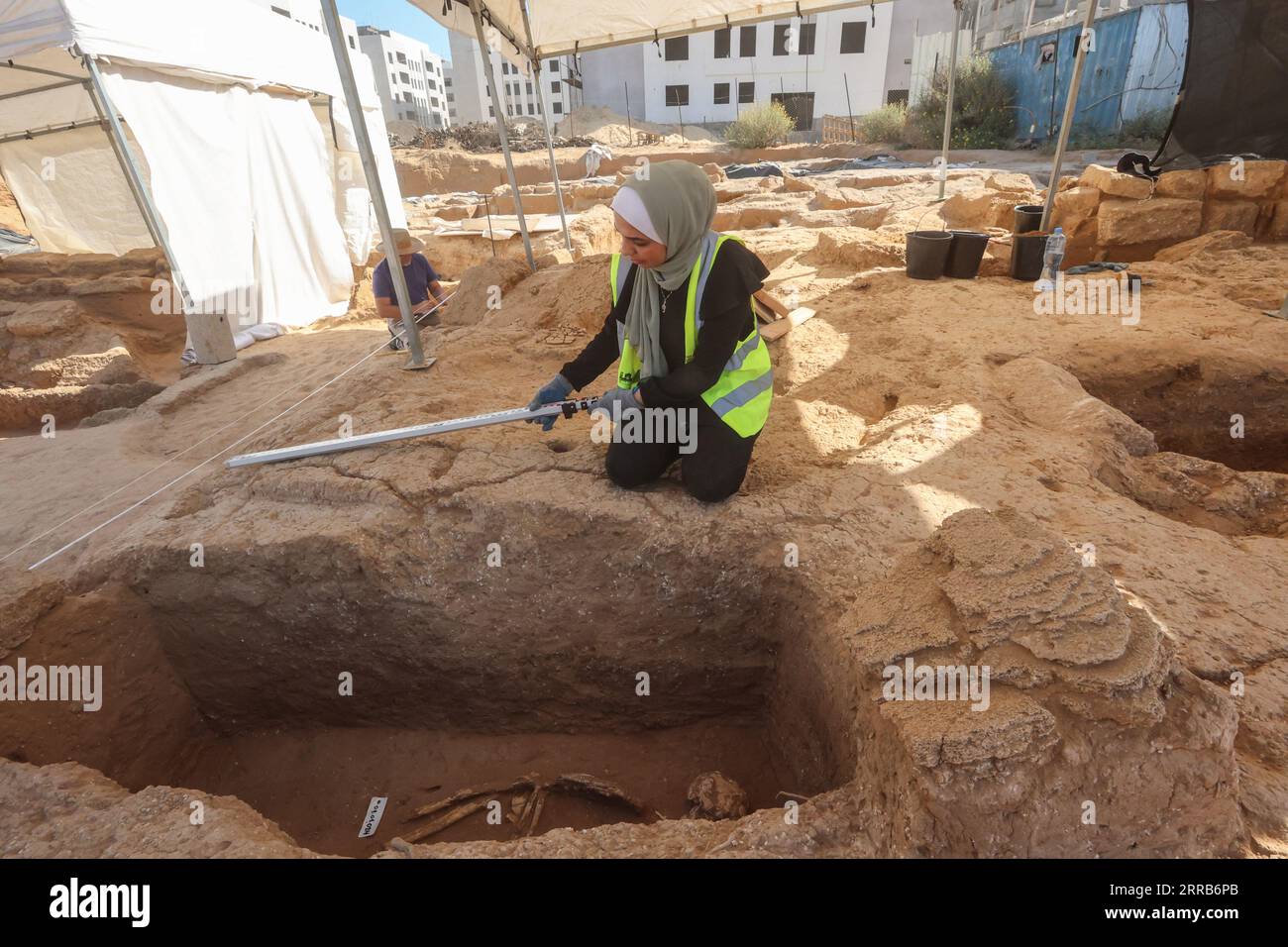A Palestinian archaeologist works near a grave full of bones at the ...