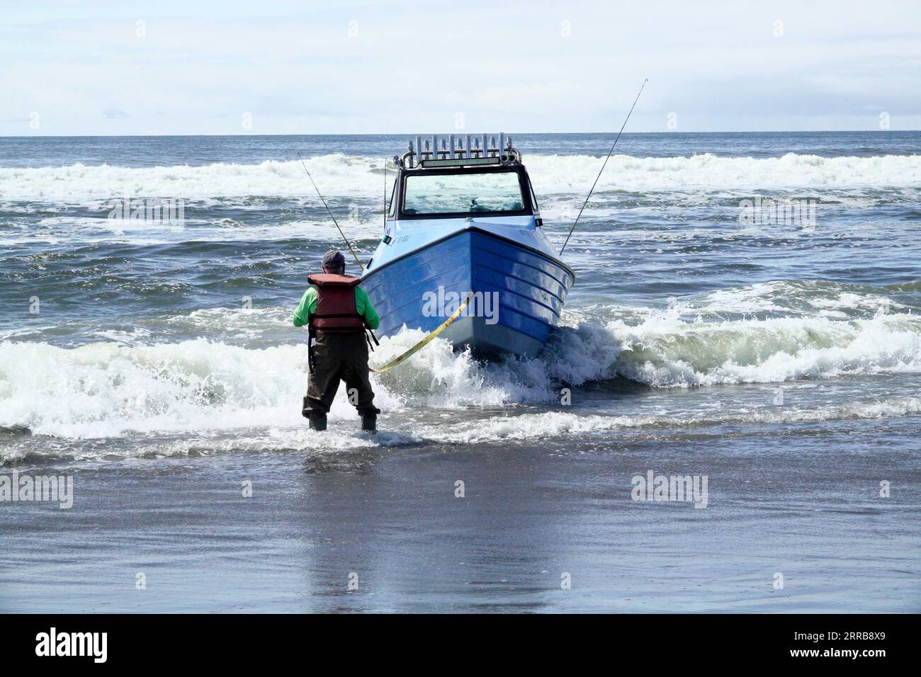 Fisherman in a dory launches his boat on the beach, near Seaside ...