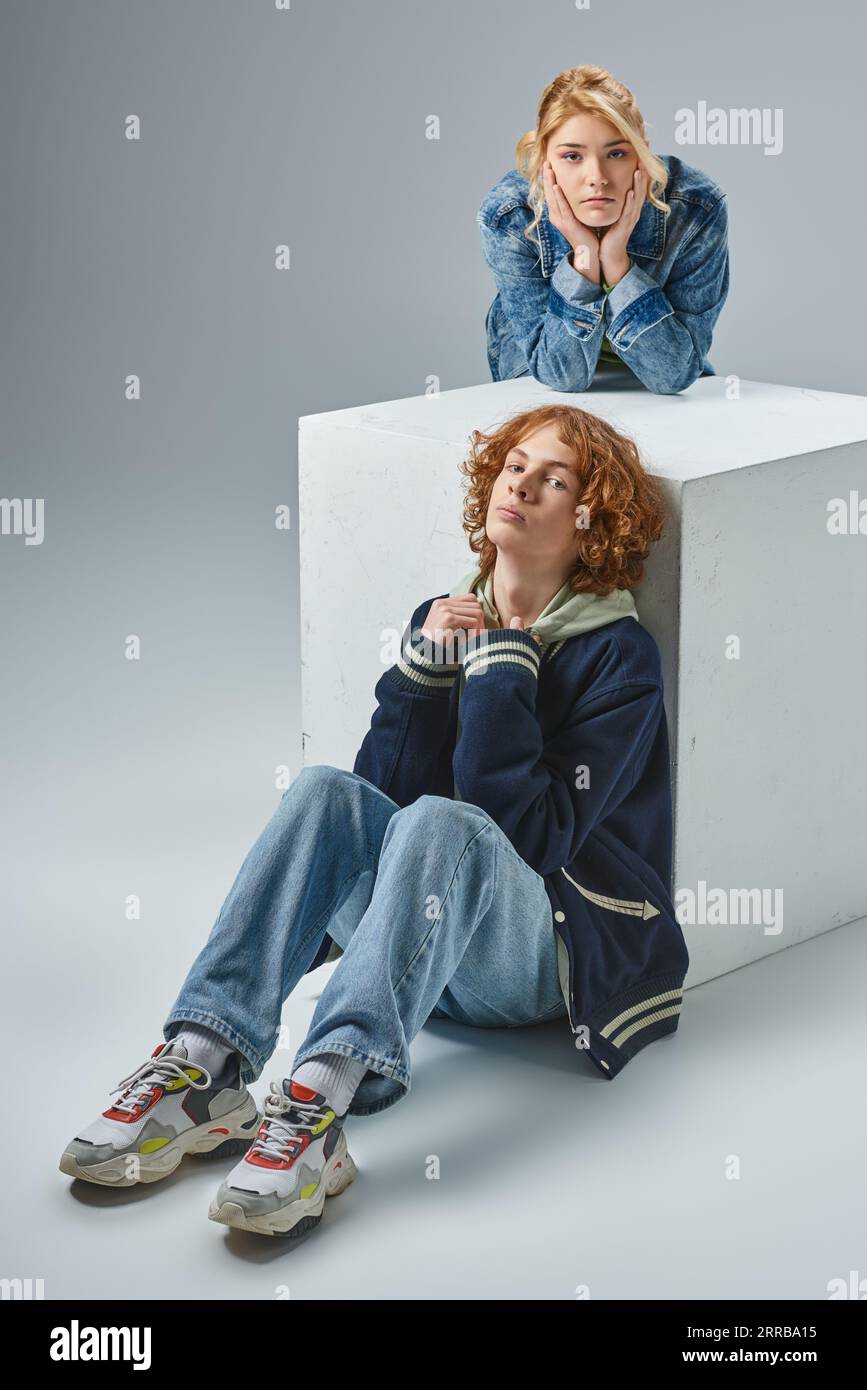 teenage models in stylish casual attire posing near white cube and ...