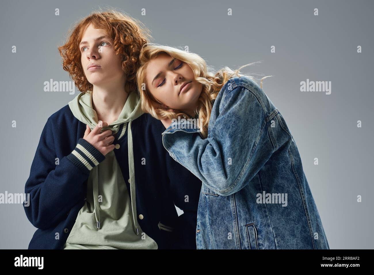 blonde teenage girl with closed eyes leaning on stylish redhead ...
