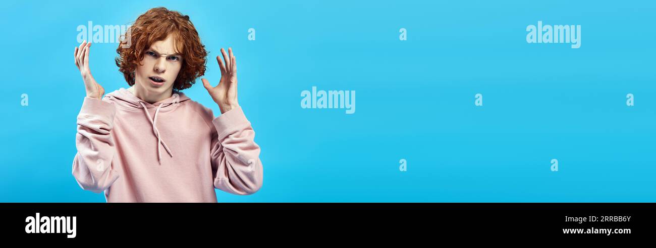 angry teenage guy with red wavy hair looking at camera and gesturing on ...