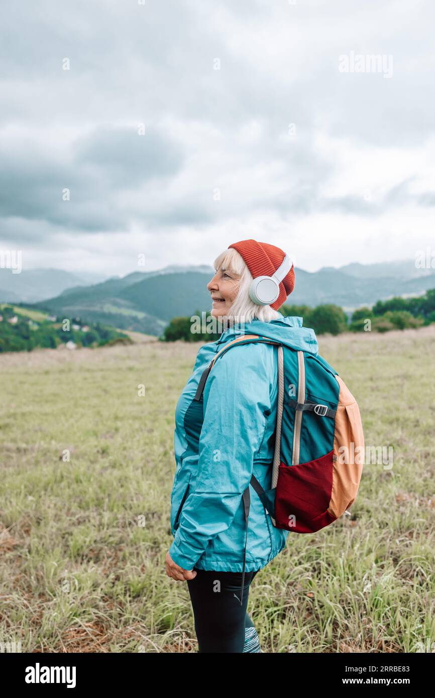 Happy active senior tourist woman listening to music in outdoor leisure ...