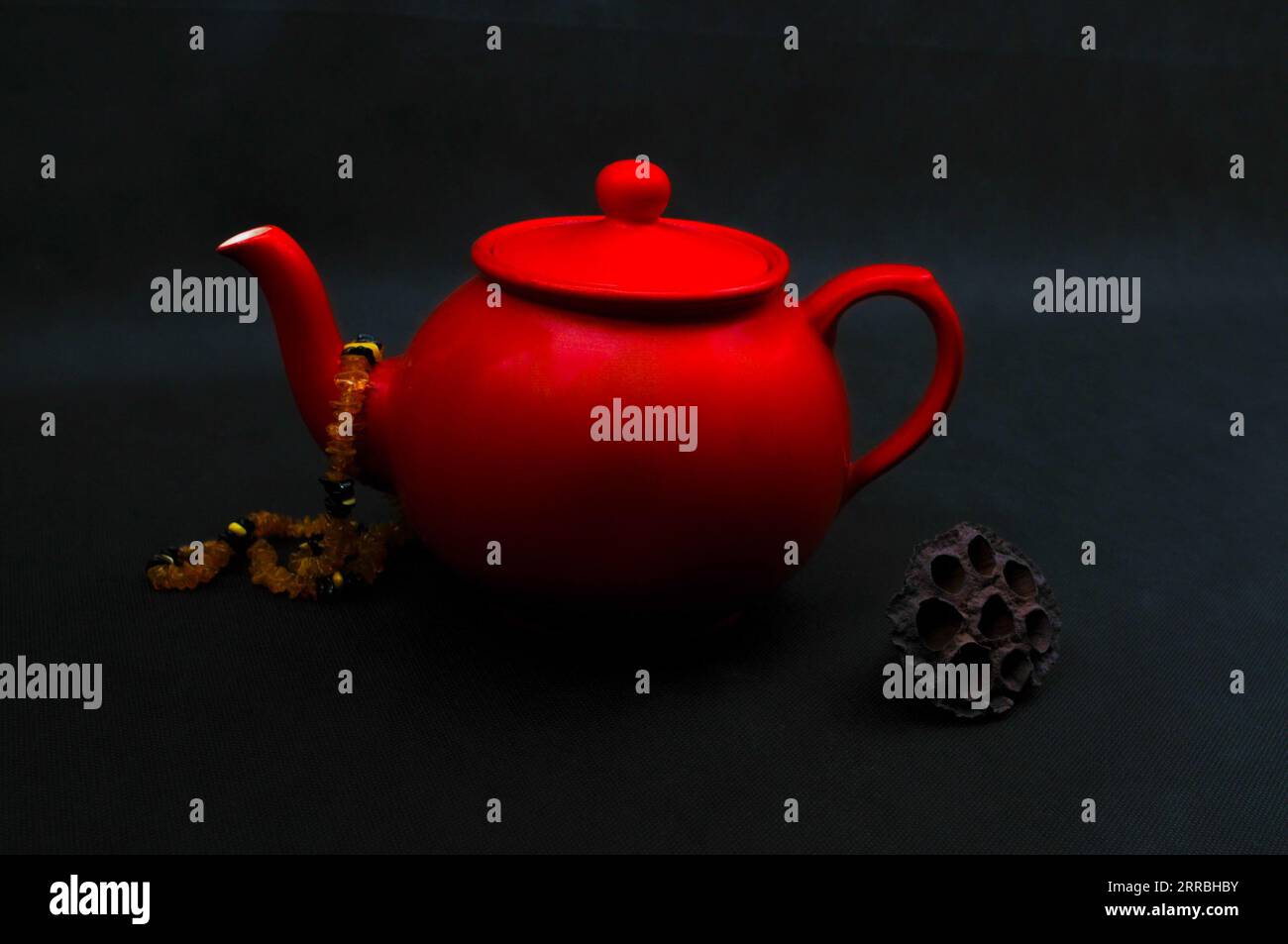 Red tea pot in a black background. With amber neckless Stock Photo - Alamy