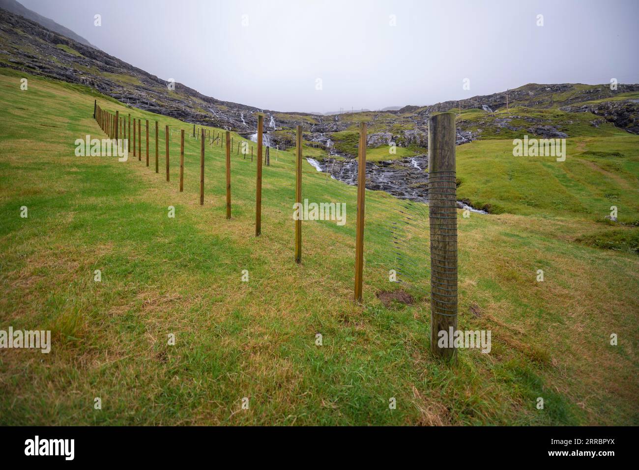 Water cascades down a slope above the village of Tjørnuvik in the Faroe ...