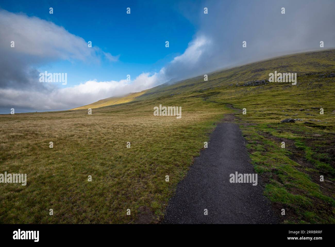 A hiking path leads up a steep slope on Eysteroy island on the Faroe ...