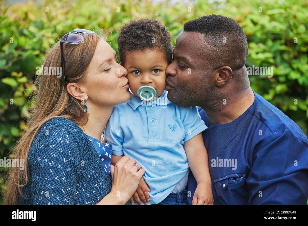 Tilst, Denmark, 12th of August: Interracial parents kiss son Stock ...