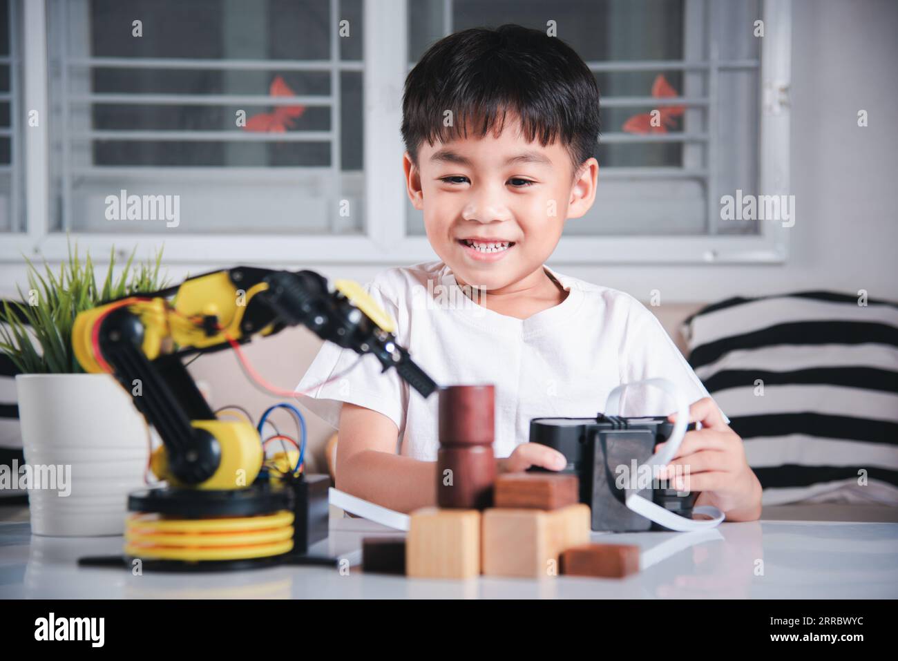 Happy Asian little kid boy using remote control playing robotic machine ...