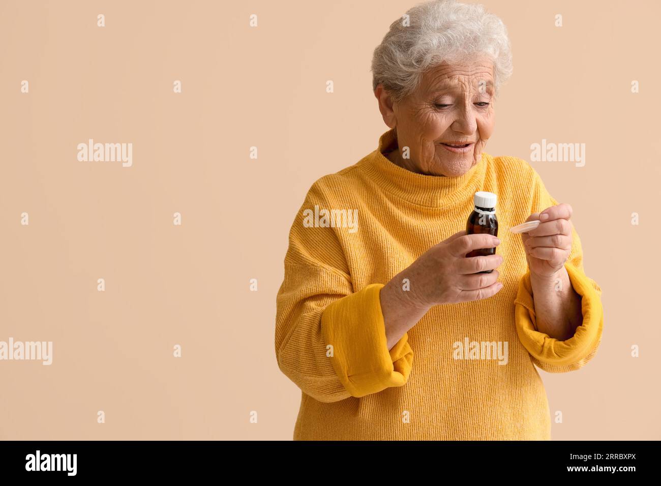 Ill senior woman taking cough syrup on beige background Stock Photo - Alamy