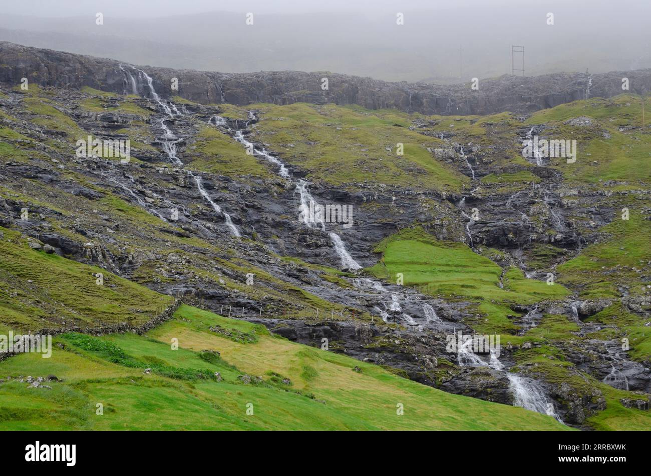 Water cascades down a slope above the village of Tjørnuvik, in the ...