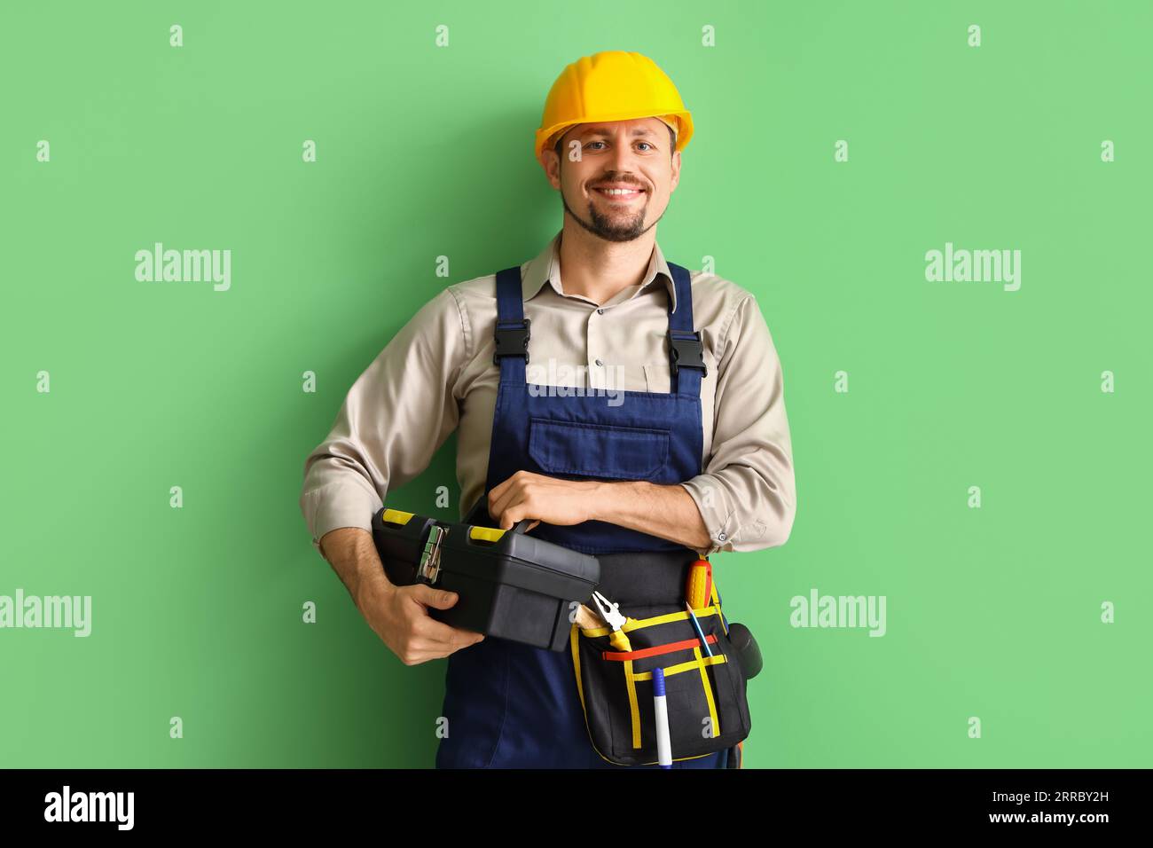 Male builder with tool bag on green background Stock Photo - Alamy