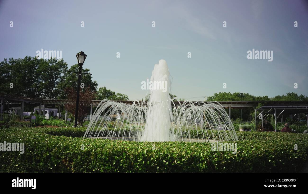 A tranquil scene of a small water fountain illuminated by the ambient ...