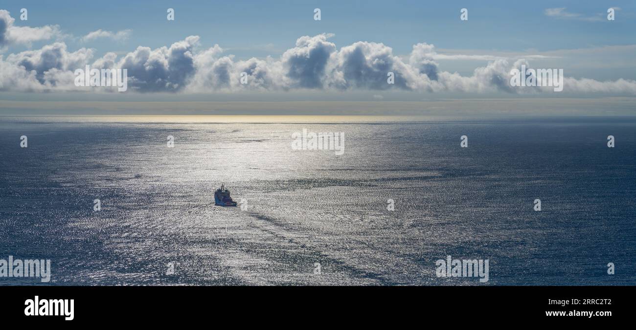 panorama view of a ship heading out to sea with bright morning sun ...