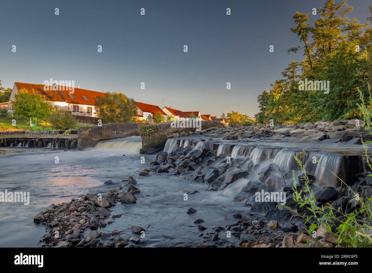 Big weir in Budweis with blue sky and small countryside buildings in ...